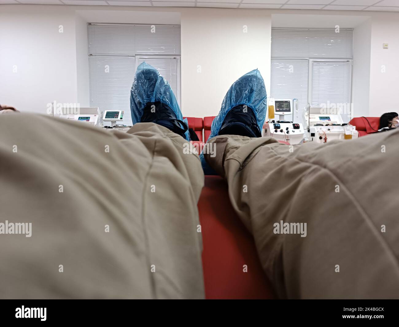 Legs shod in boots and blue shoe covers. Shoe covers on the legs close ...