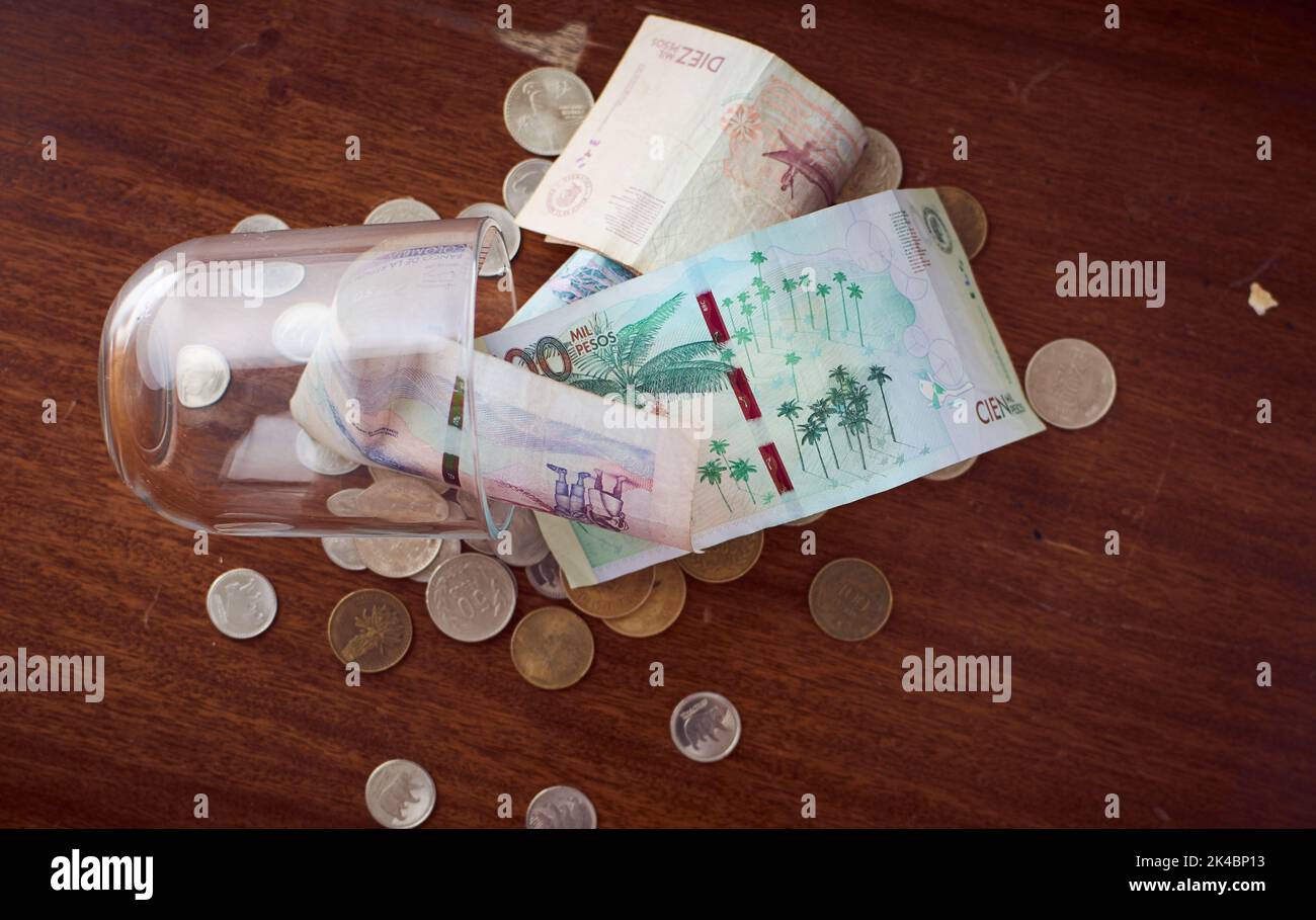 A top view shot of Colombia peso banknotes and coins currency in fallen ...
