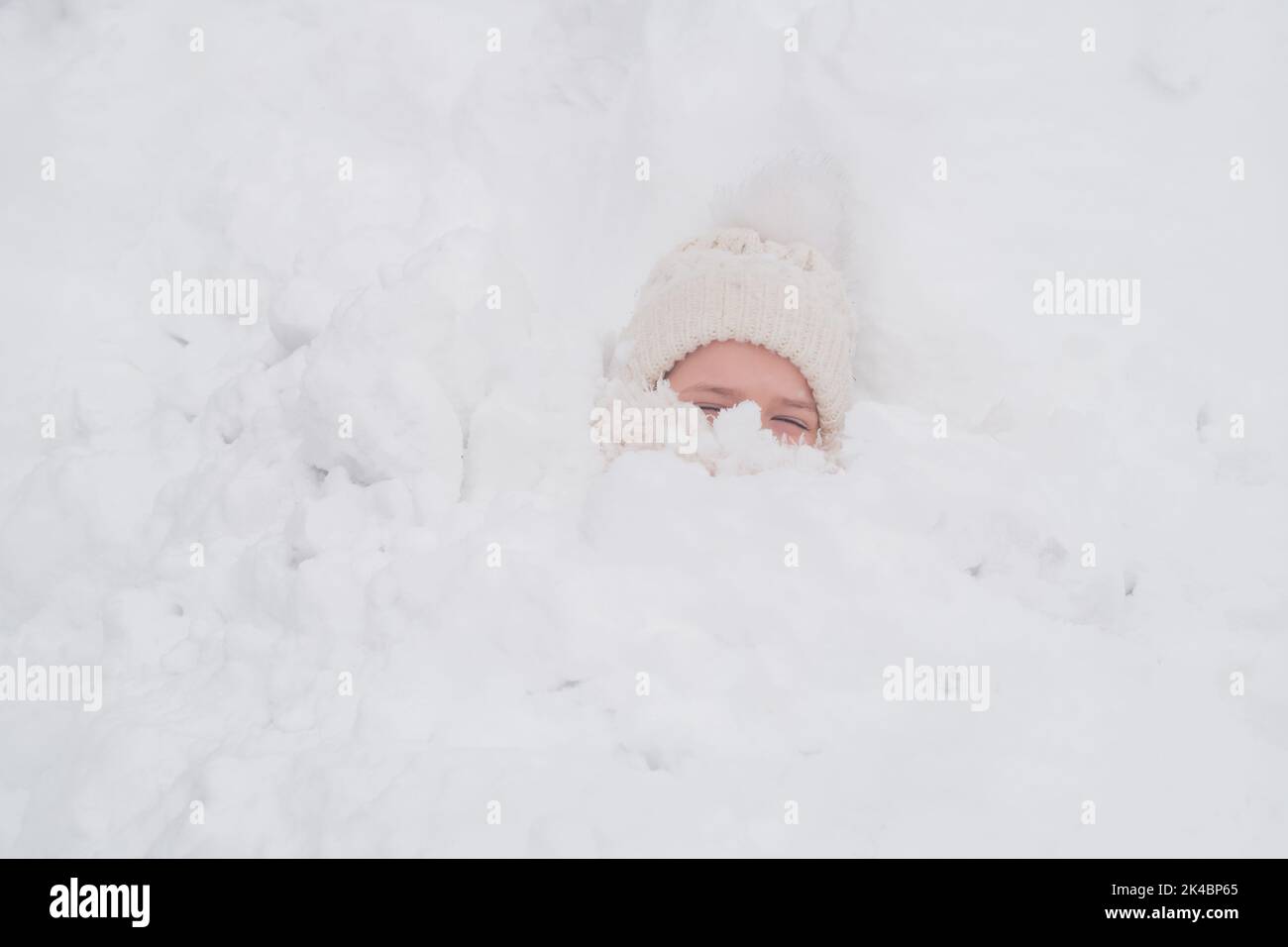 Child, 6 years old boy playing and hiding in the snow. All body covered ...