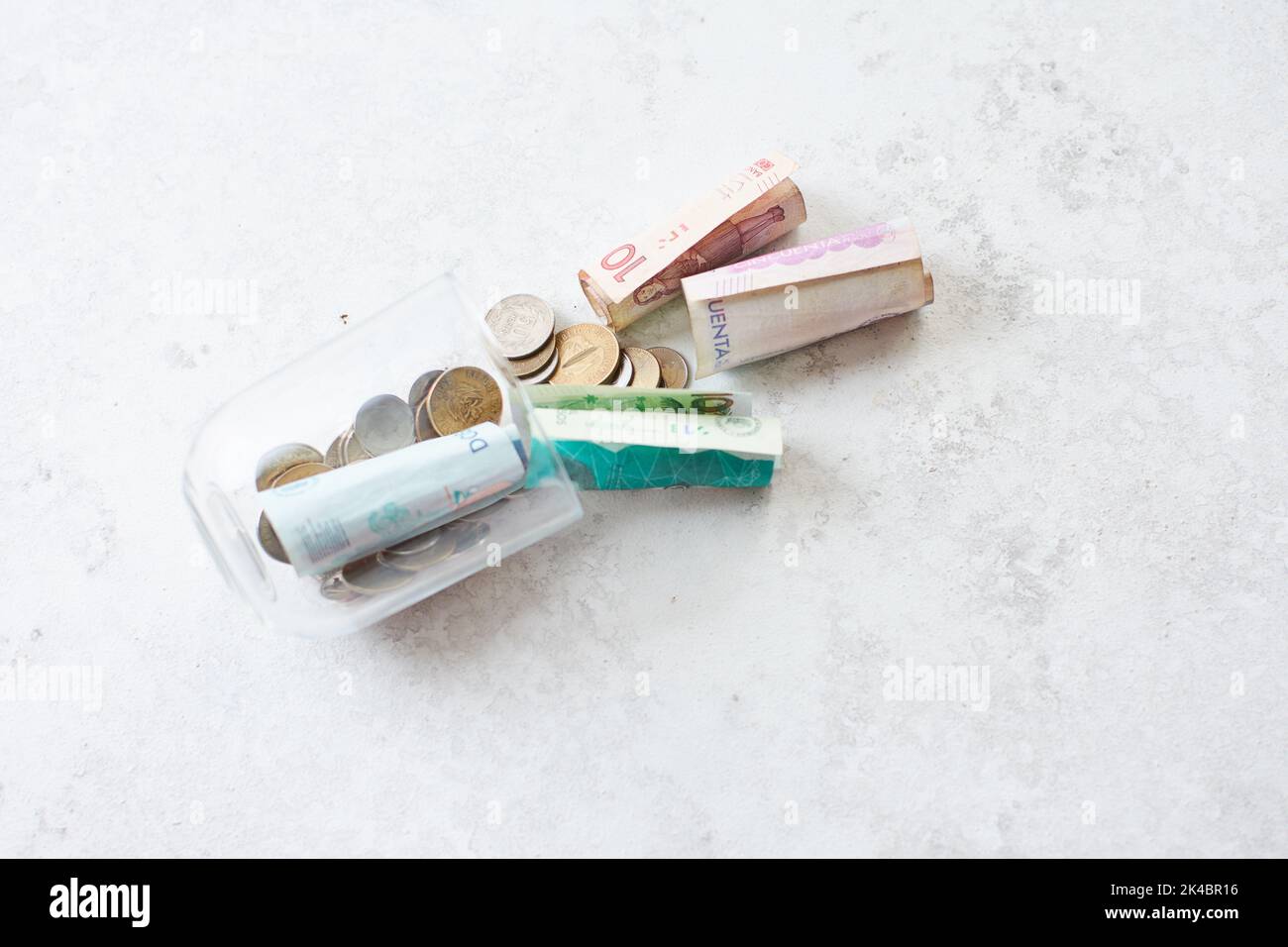 A top view shot of glass cup Colombia Peso banknotes and coins out on a ...