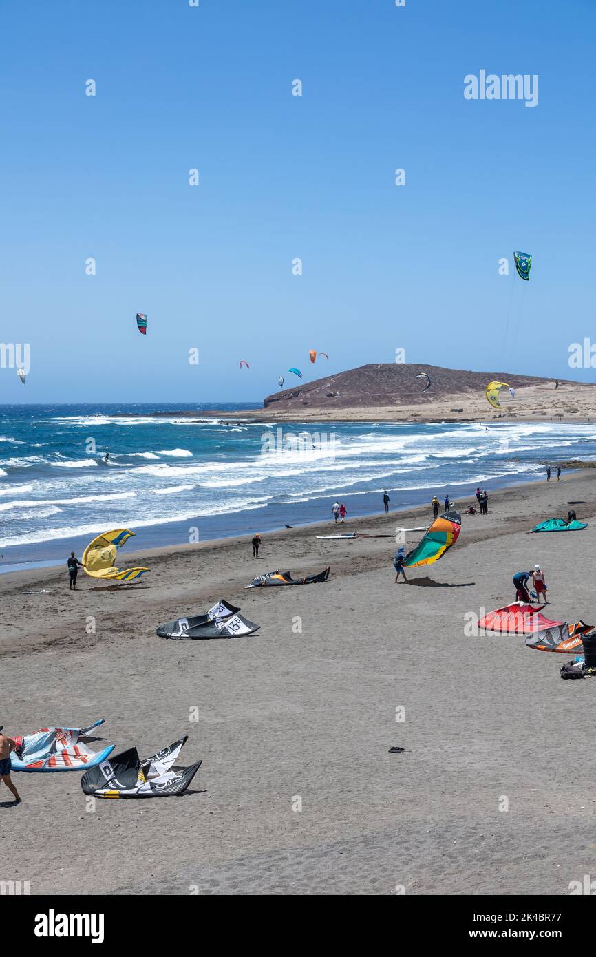 A vertical shot of the coast of a beach while people are kitesurfing ...