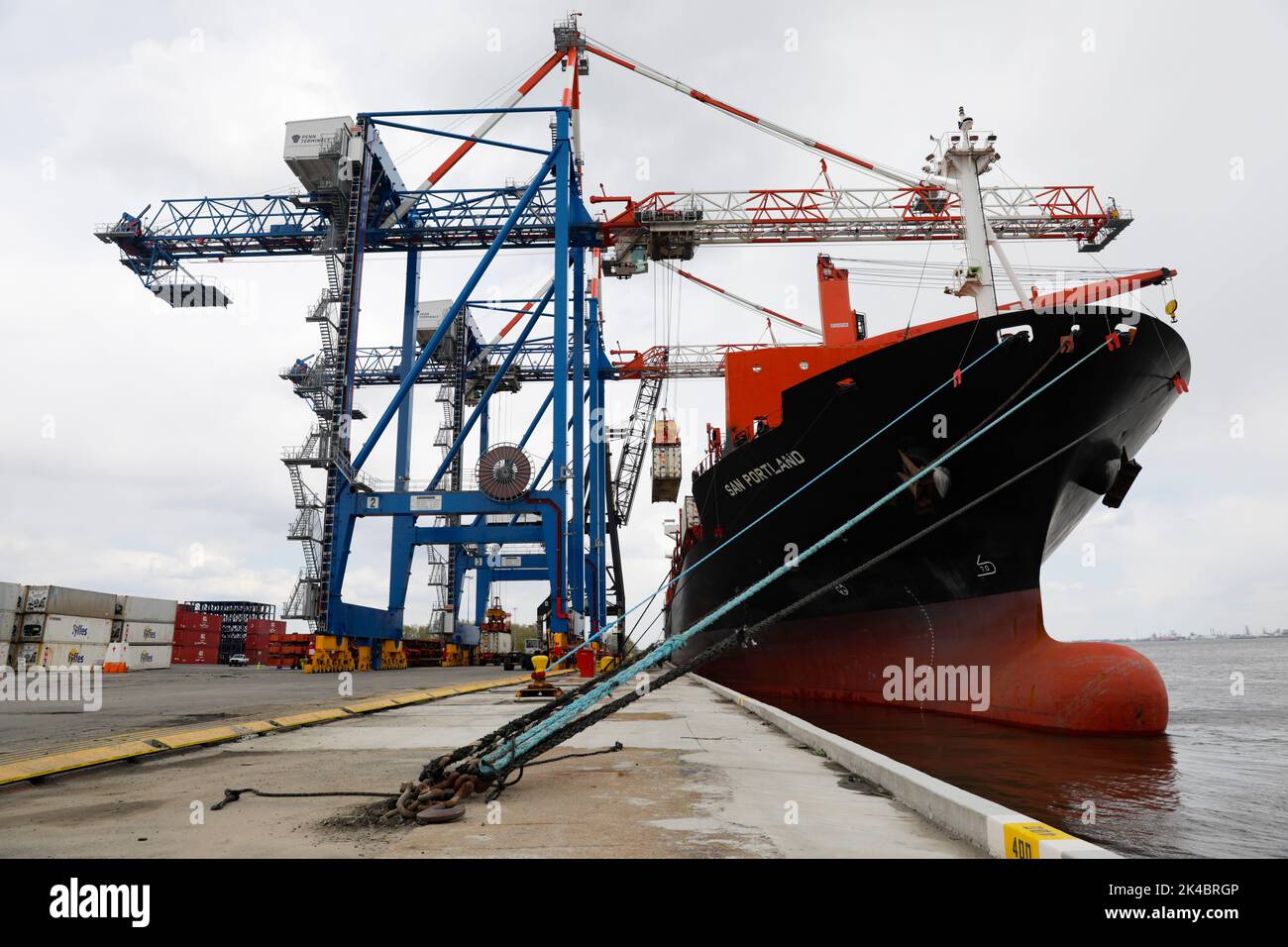 A cargo ship is offloaded by massive cranes at Penn Terminals in ...