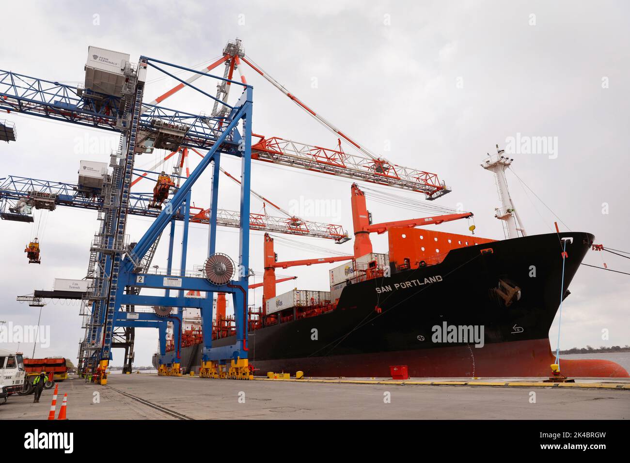 A cargo ship is offloaded by massive cranes at Penn Terminals in ...