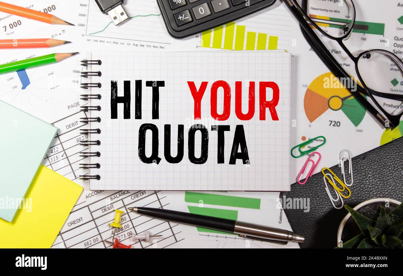 Closeup on businessman holding a card with text HIT YOUR QUOTA ...