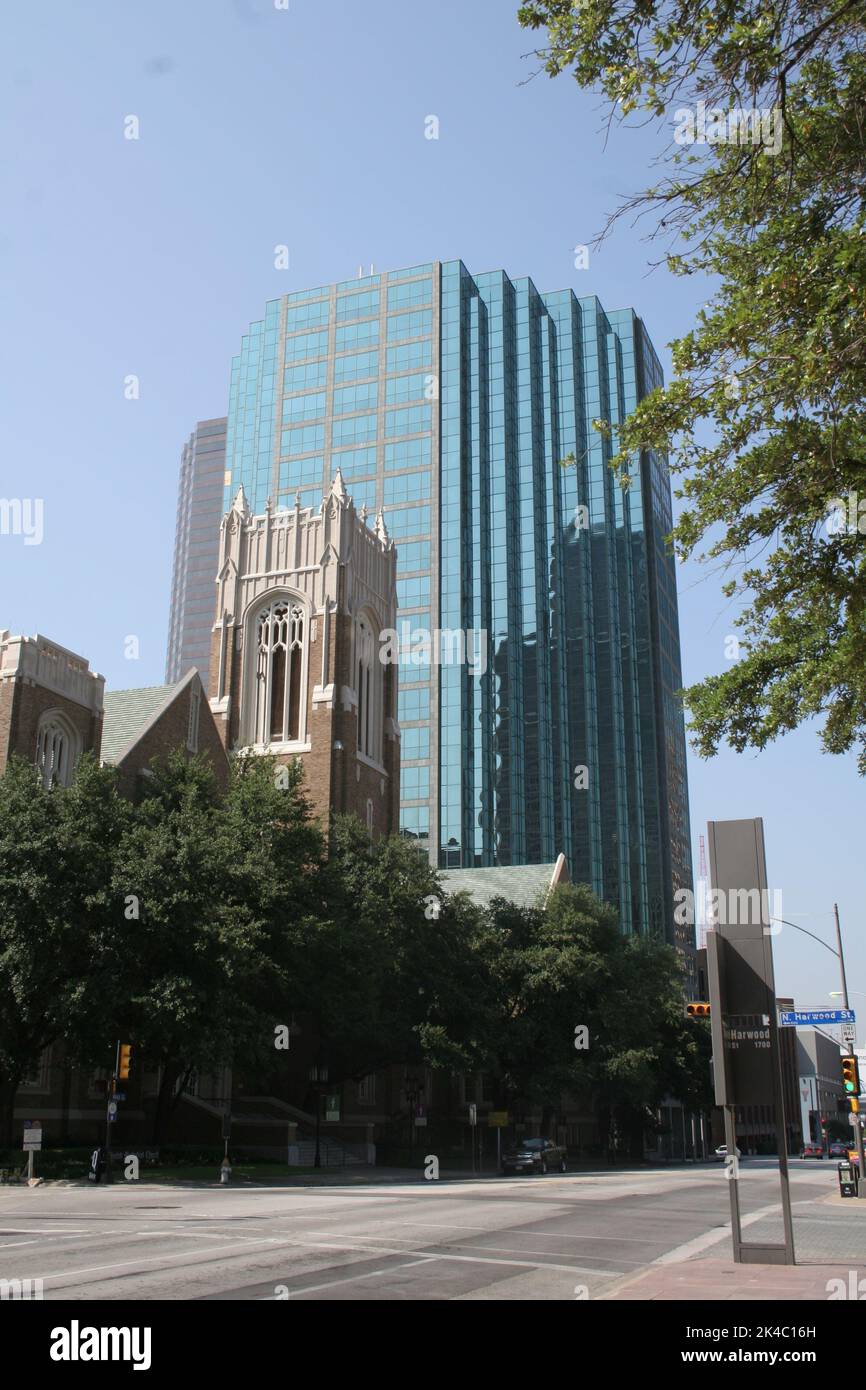A tall skyscraper with blue glass walls looming over an old stone ...