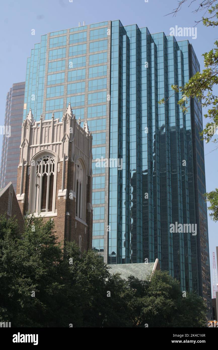 A tall skyscraper with blue glass walls looming over an old stone ...