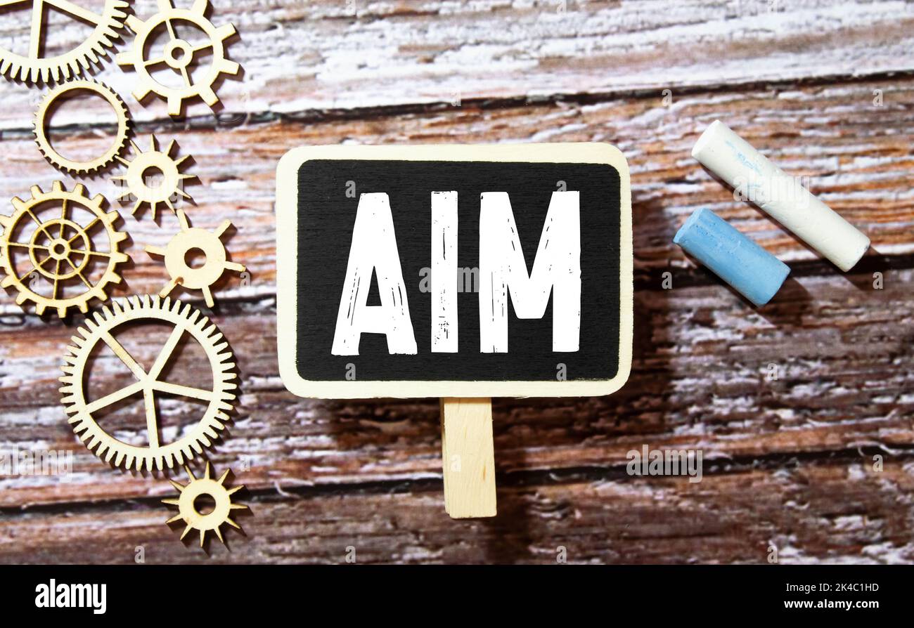 The word Aim on a strip of white paper. A red dart will be stuck in the ...