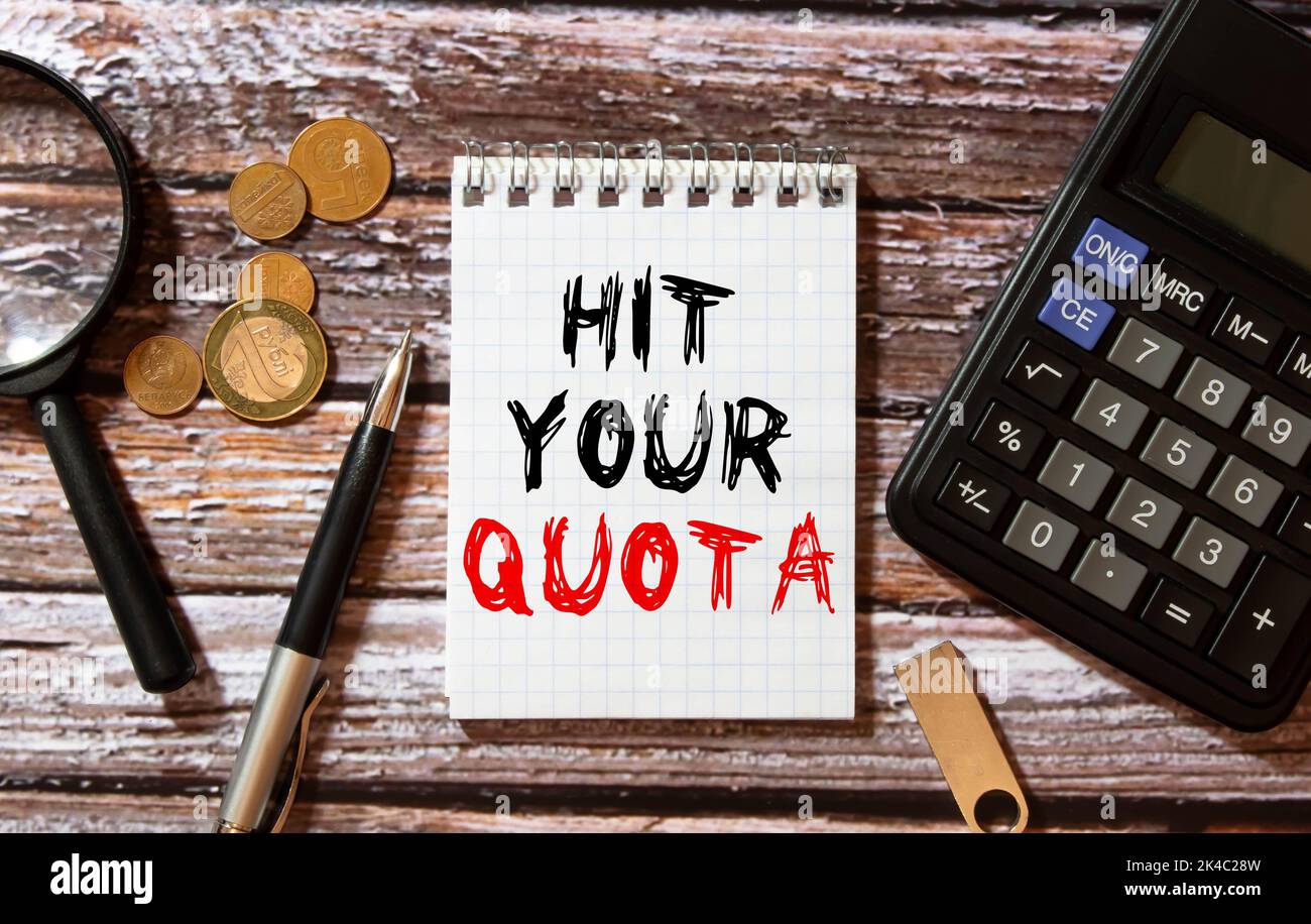 Closeup on businessman holding a card with text HIT YOUR QUOTA ...