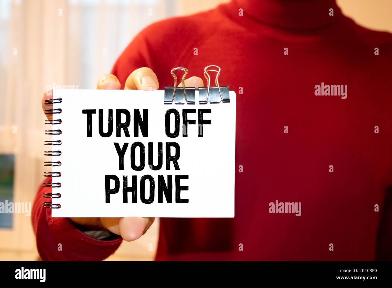 Closeup on businessman holding a card with text TURN OFF YOUR PHONE ...