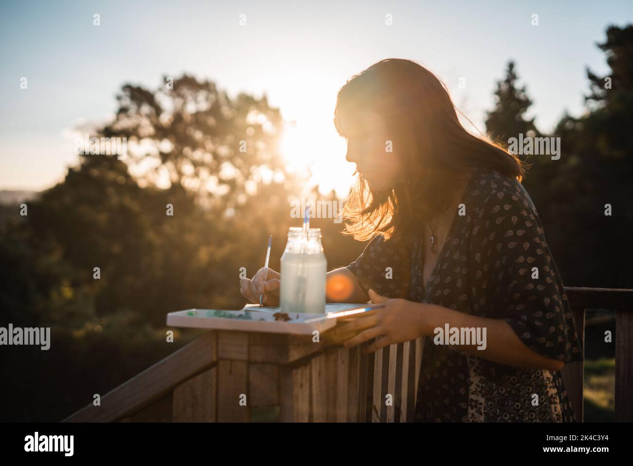 Girl standing painting a canvas at sunset Stock Photo - Alamy