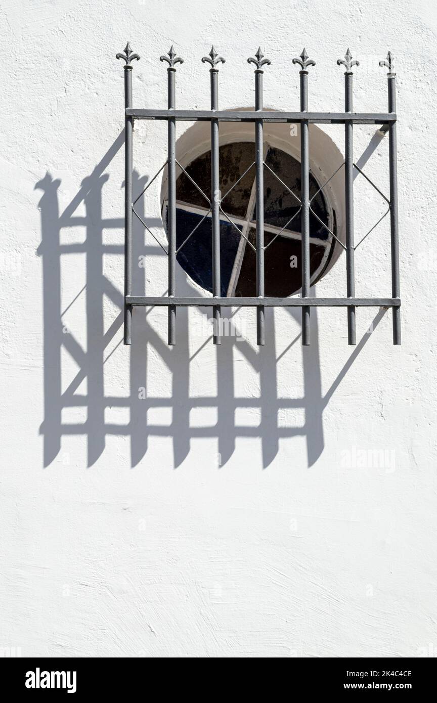 Window grille with spikes. Round glass window surrounded by metal in ...