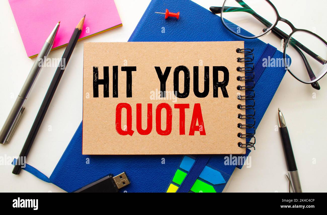 Closeup on businessman holding a card with text HIT YOUR QUOTA ...