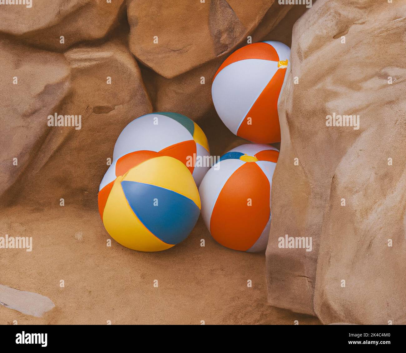 Four beach balls stuck between big rocks at the beach Stock Photo - Alamy