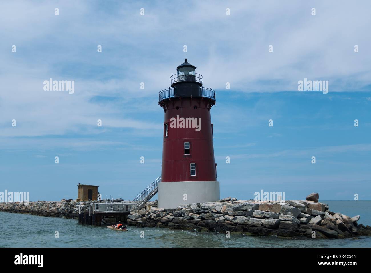 A lighthouse in the sea with pile of big rock pathway Stock Photo - Alamy