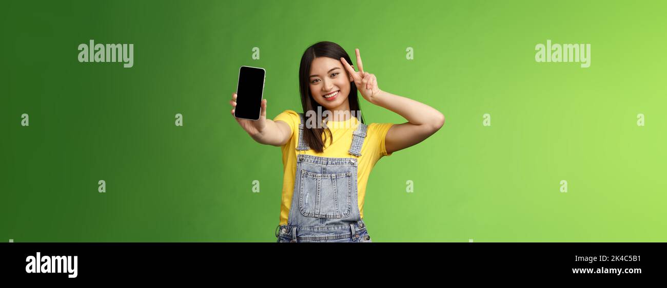 Cute carefree asian brunette showing application on smartphone screen ...