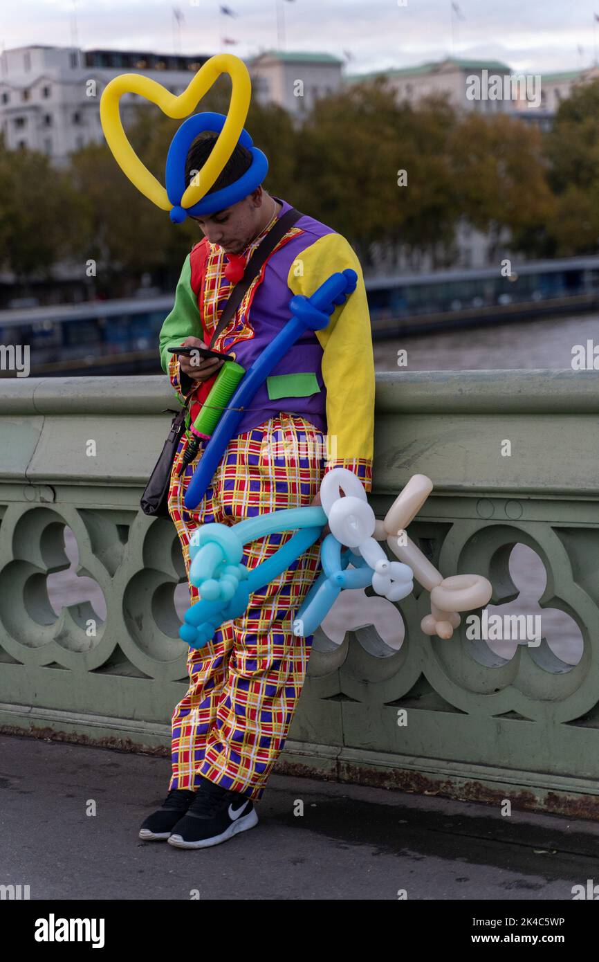 A street performer as a clown chilling on a bridge Stock Photo - Alamy