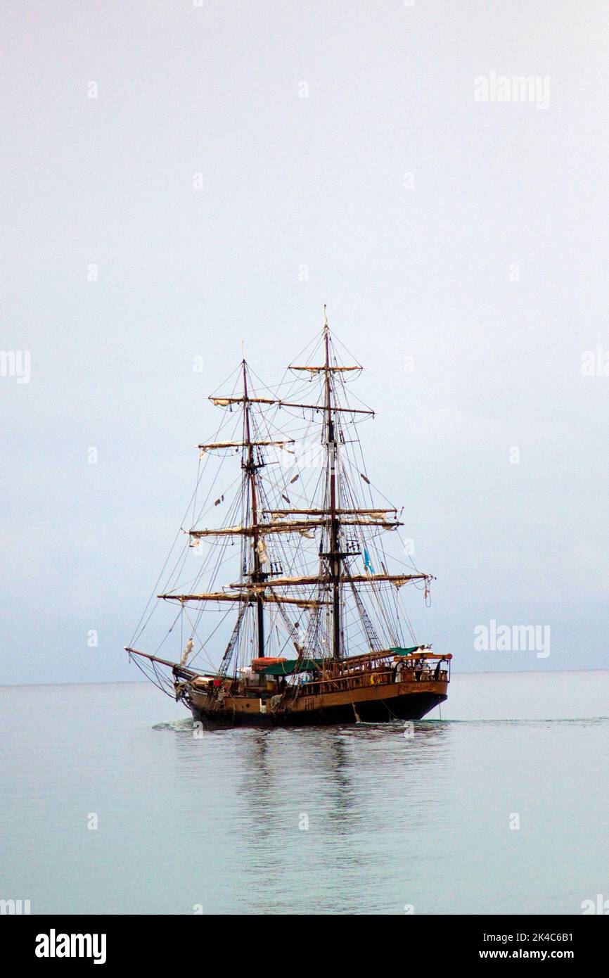 A vertical shot of two-masted wooden ship sailing in the sea under ...
