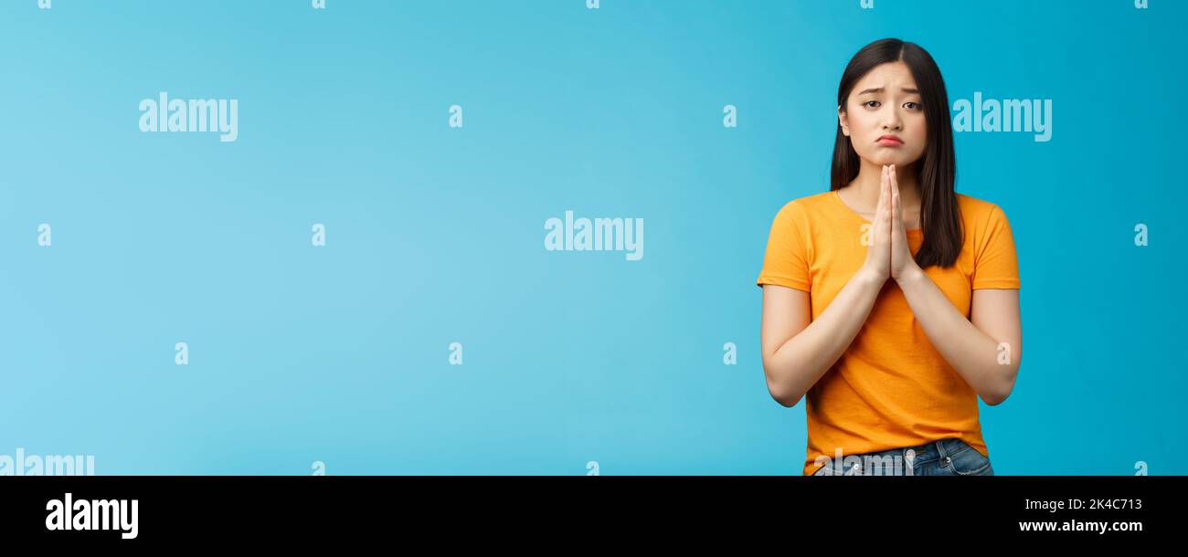 Upset cute silly asian girl praying, plead for help, pouting frowning ...