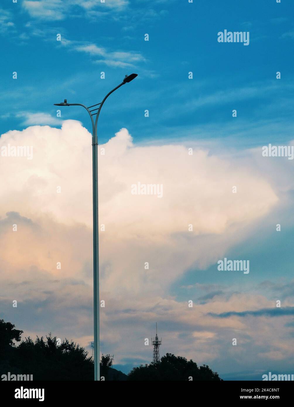 A street light pillar on the ground of huge, white clouds, vertical ...