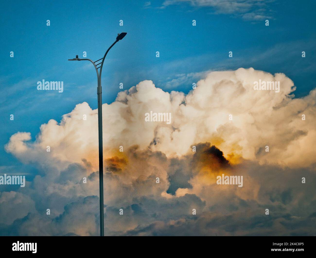 A street light pillar on the ground of huge, white clouds Stock Photo ...