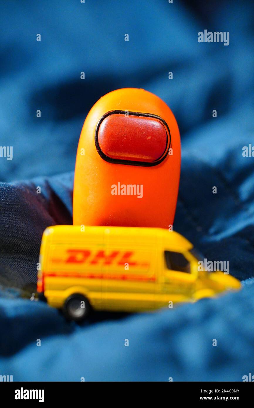 An orange colored Among Us toy model figurine and a yellow DHL model ...