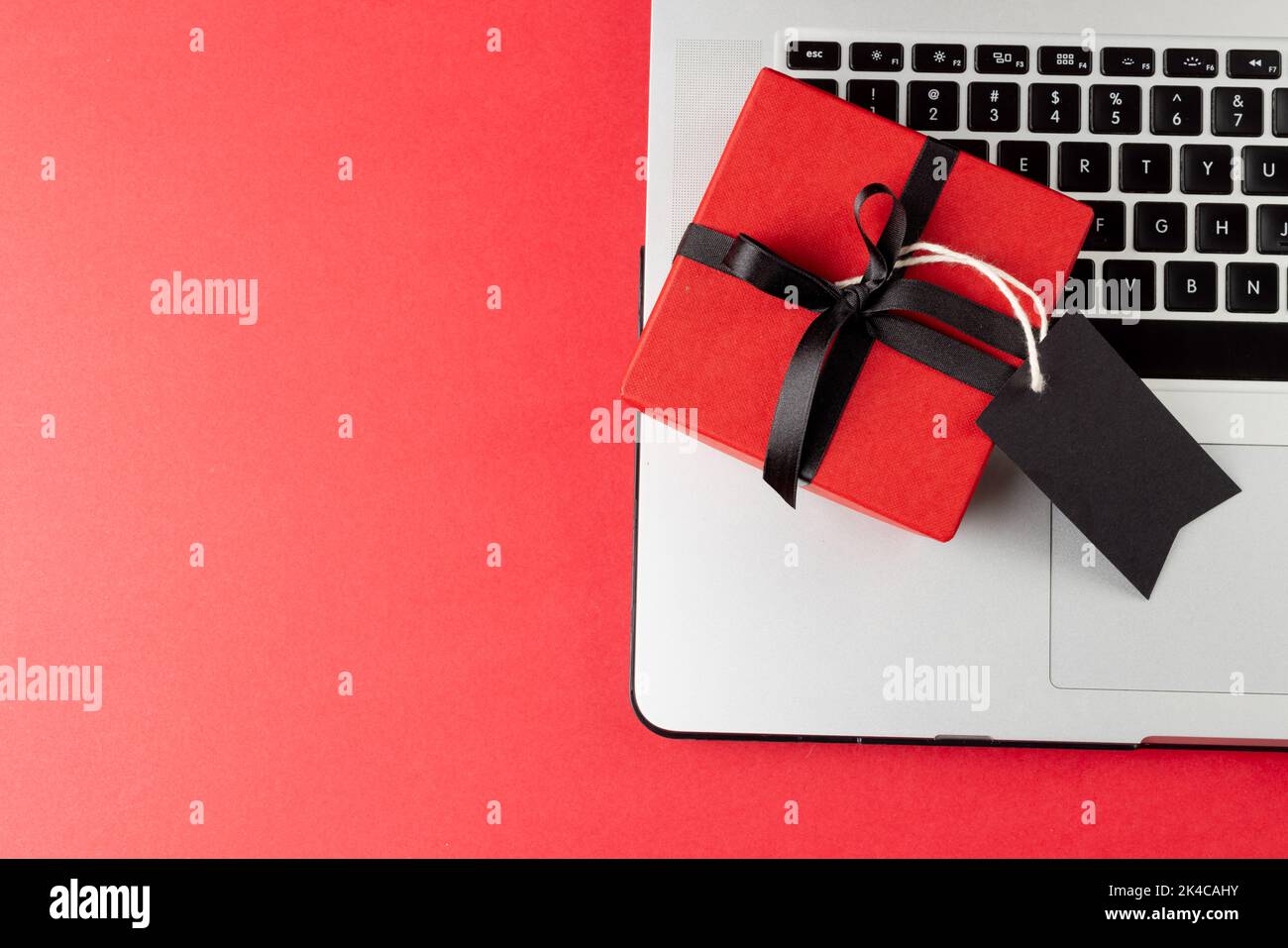 Composition of laptop with gift tag and present on pink background ...