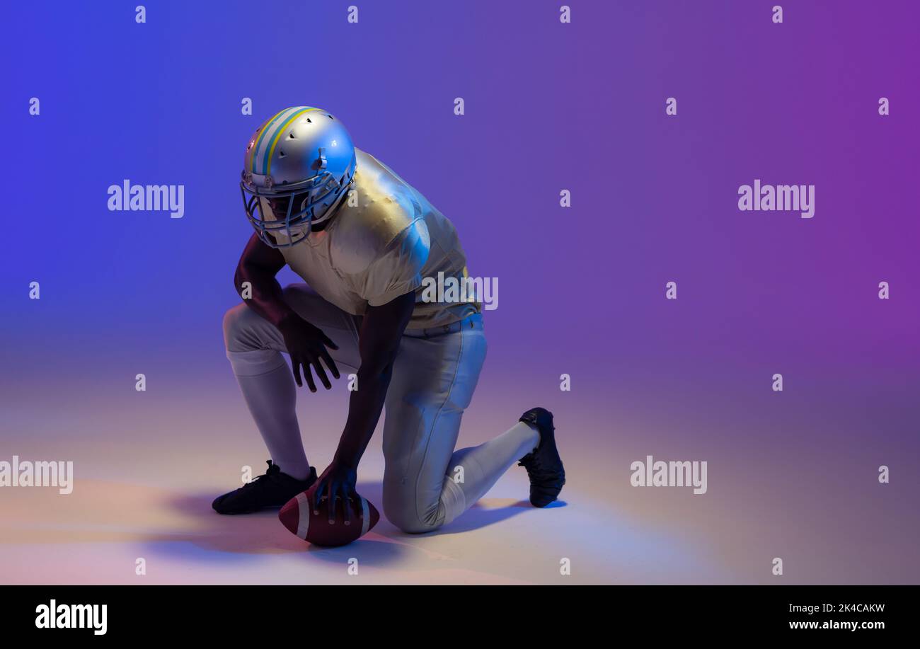 African american male american football player holding ball with neon ...