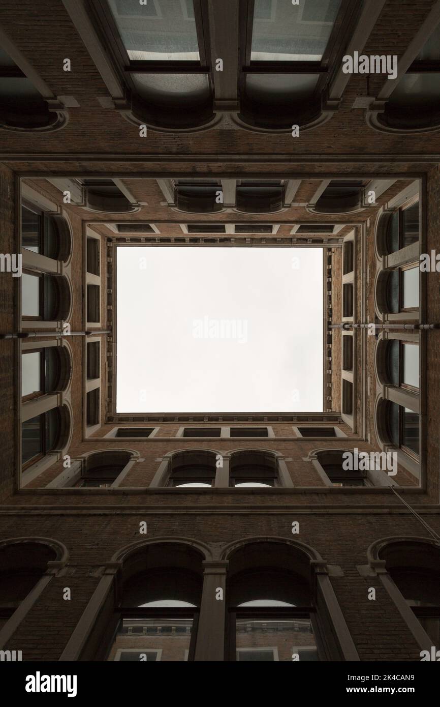 A vertical low angle shot of a building creating a suqare with white sky seen through it Stock ...
