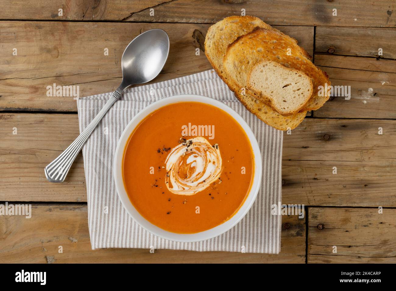 Horizontal image of bowl of tomato soup with spoon and toast on wooden ...