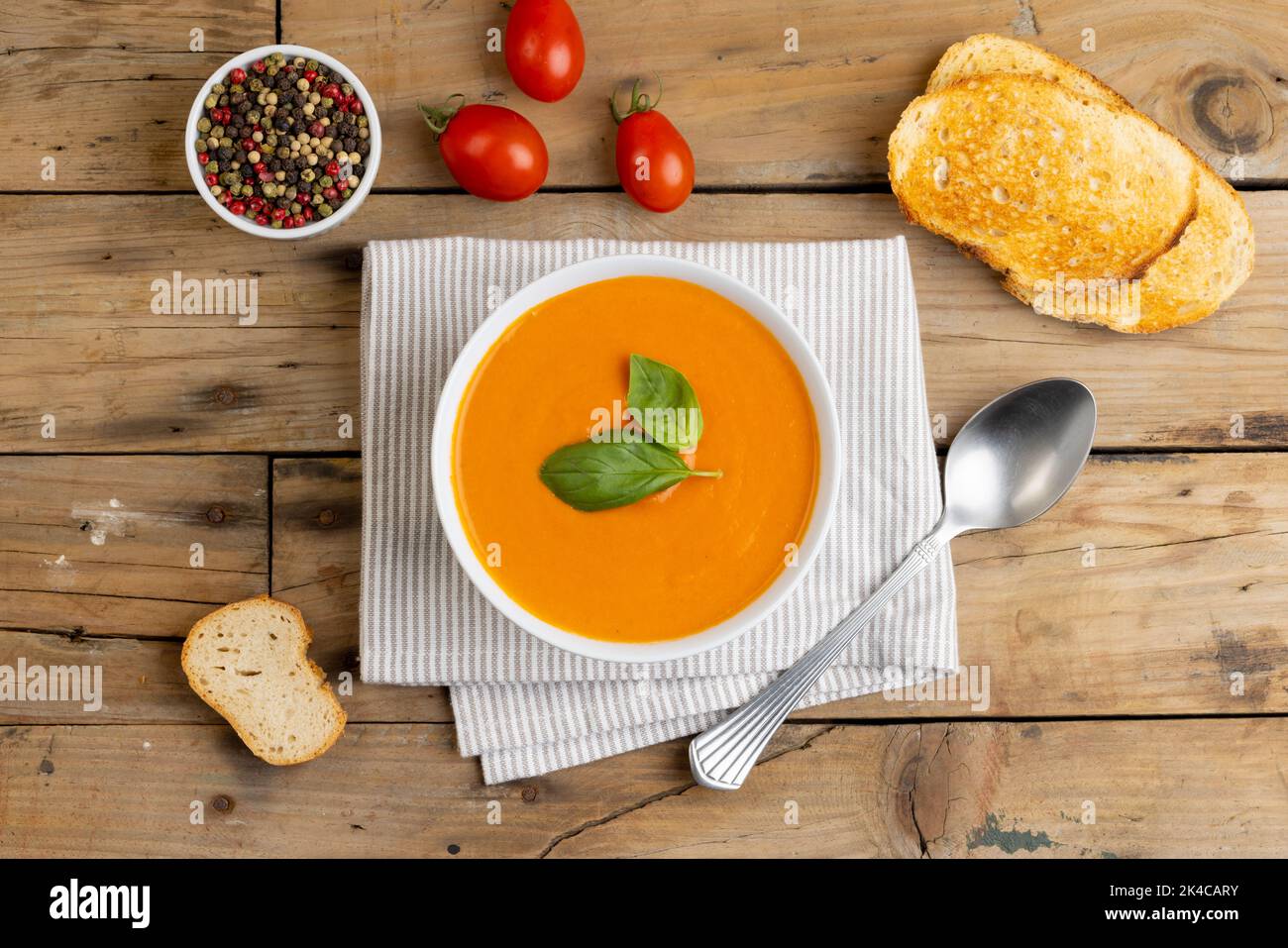 Horizontal image of bowl of tomato soup with basil garnish, tomatoes ...