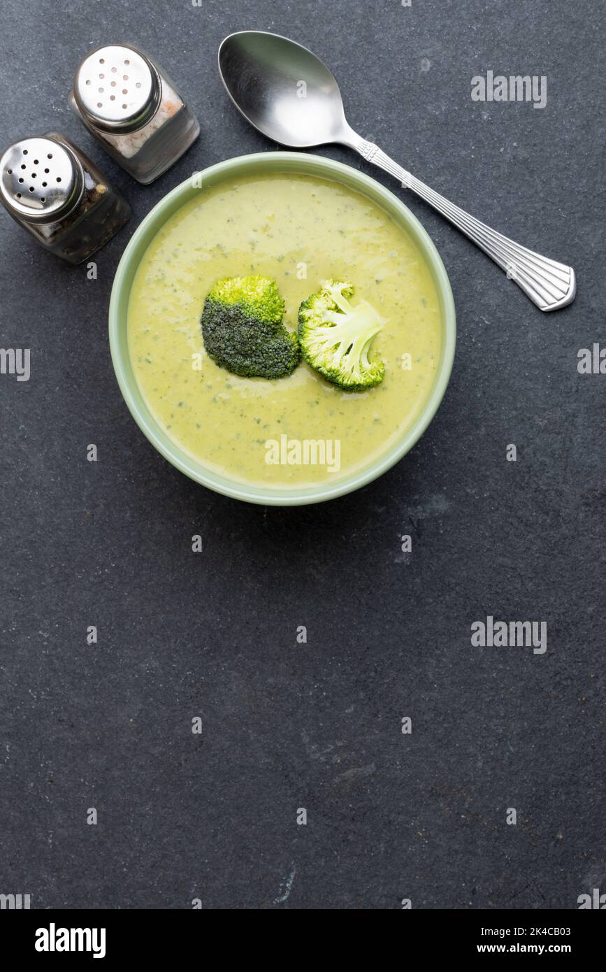 Vertical image of bowl of broccoli soup with florets, salt, pepper ...