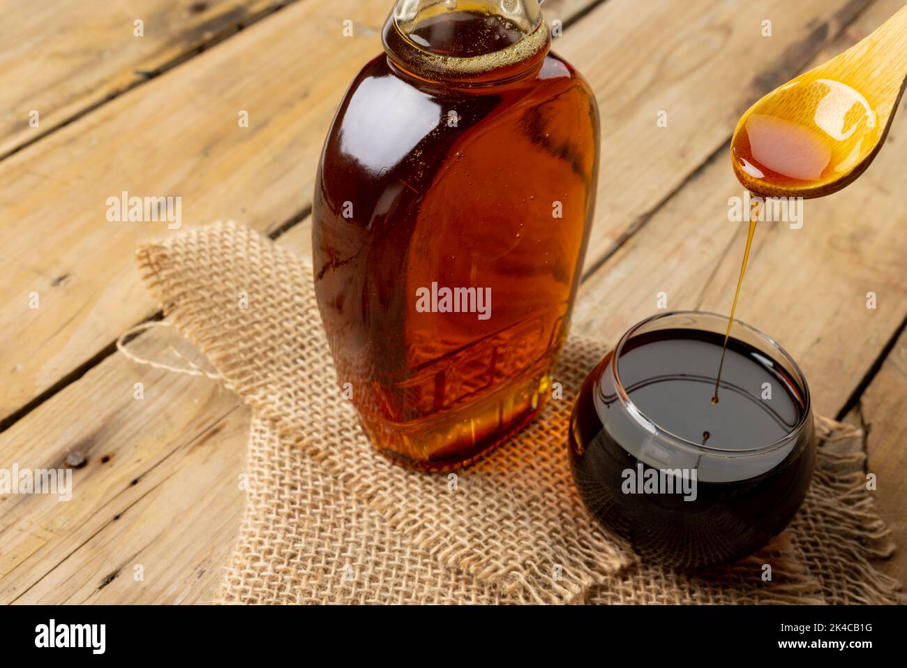 Horizontal image of bottle, wooden spoon and bowl of maple syrup on ...