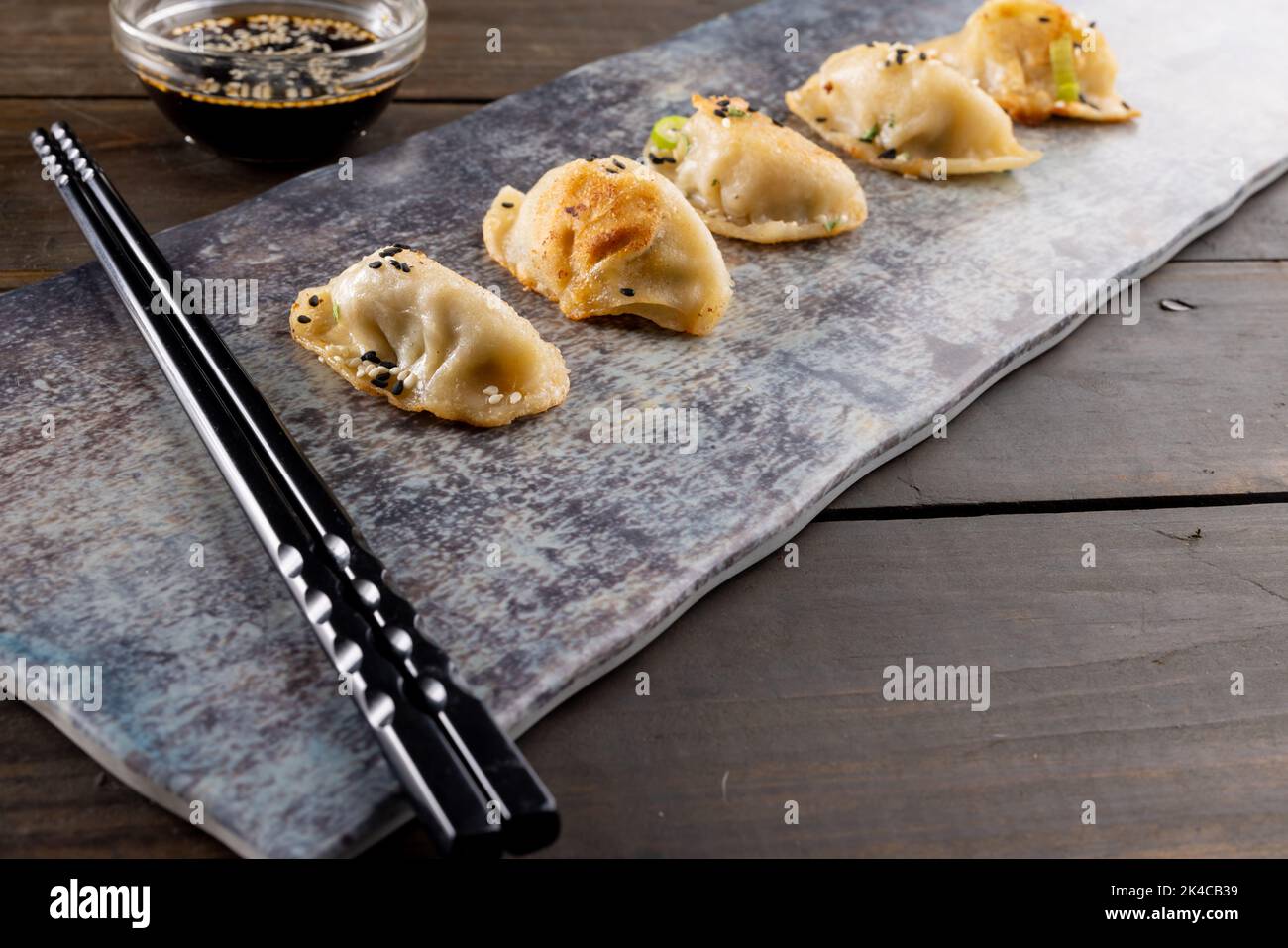Close up of asian dumplings, soy sauce and chopsticks with slate and ...