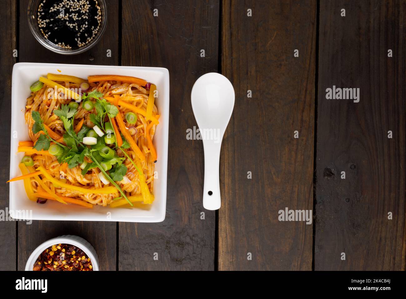 Overhead view of asian wok stir fry noodles with spoon and condiments ...