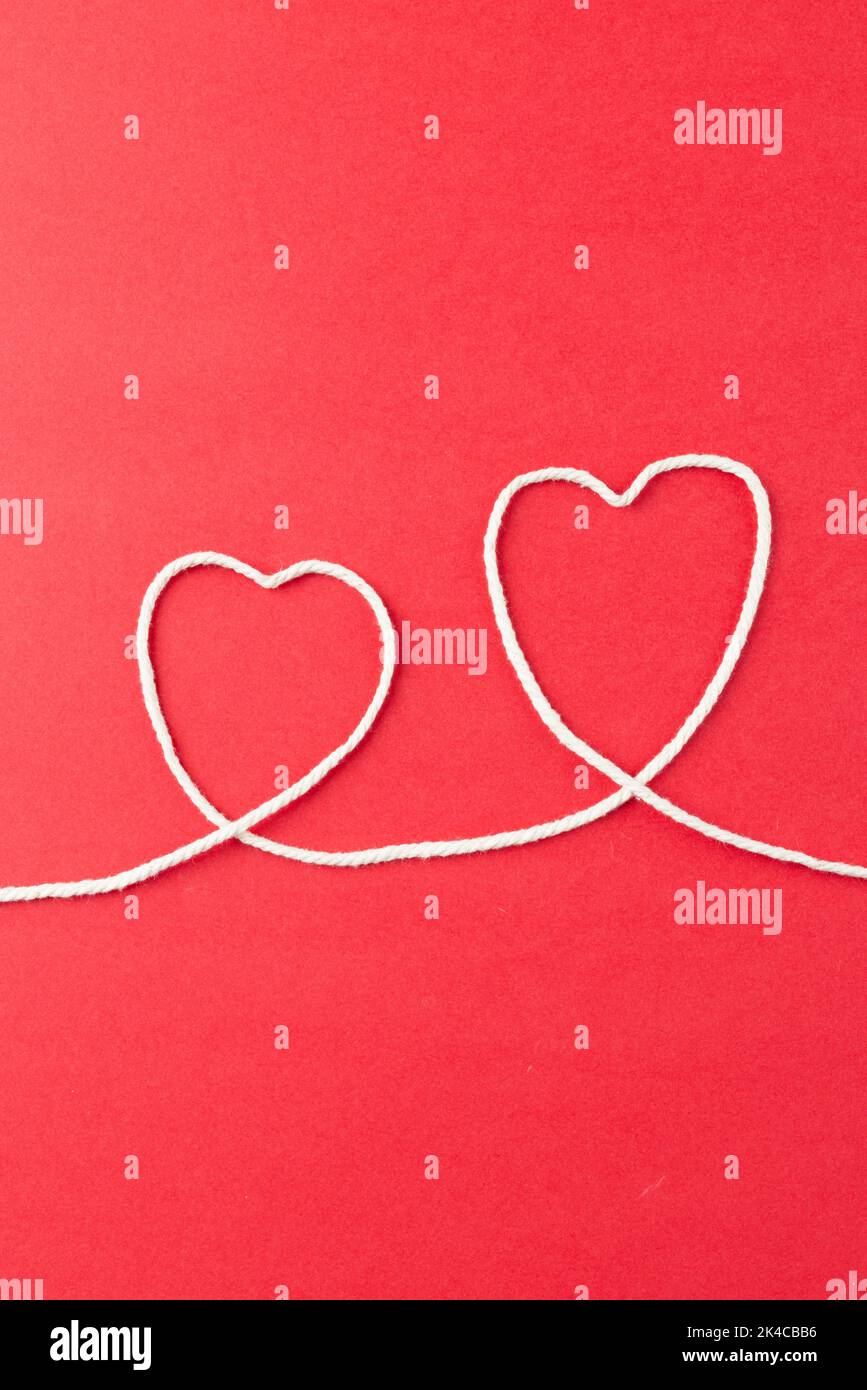 Vertical image of hearts made of white string on red surface Stock ...
