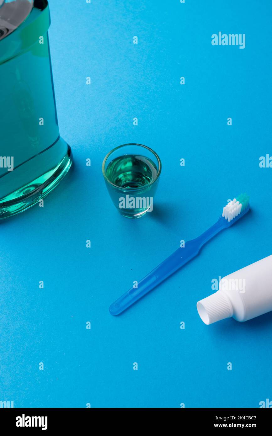 Vertical image of cleaning liquid, toothbrush and toothpaste on blue ...