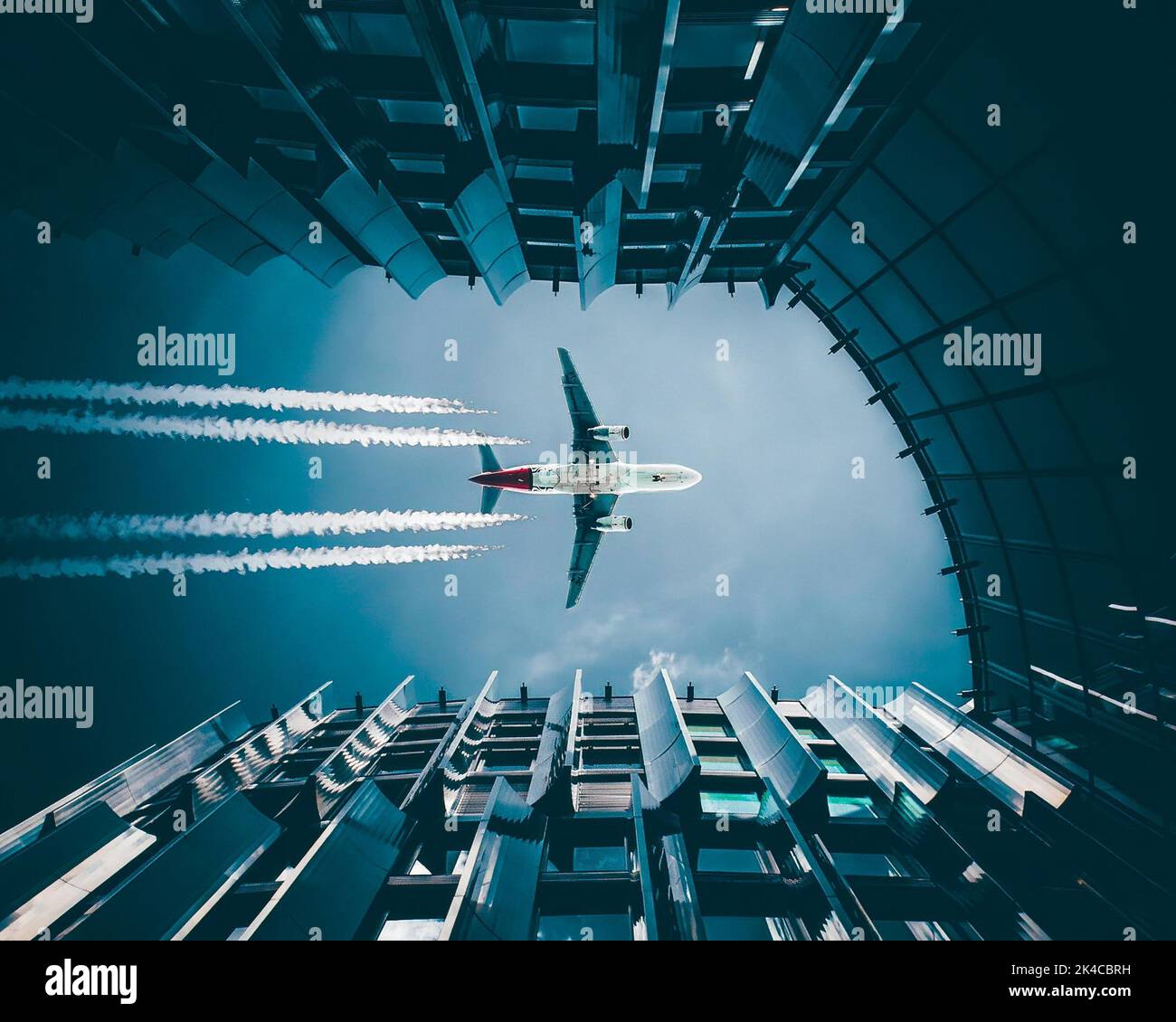 A low angle shot of a plane flying over a modern downtown building ...
