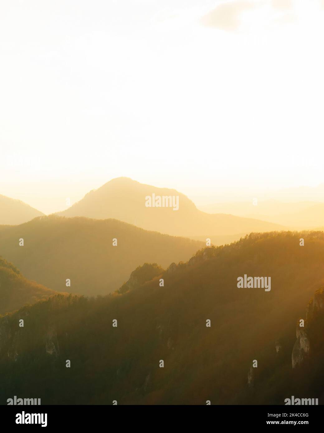 A vertical shot of silhouettes of hills and mountains under a golden ...