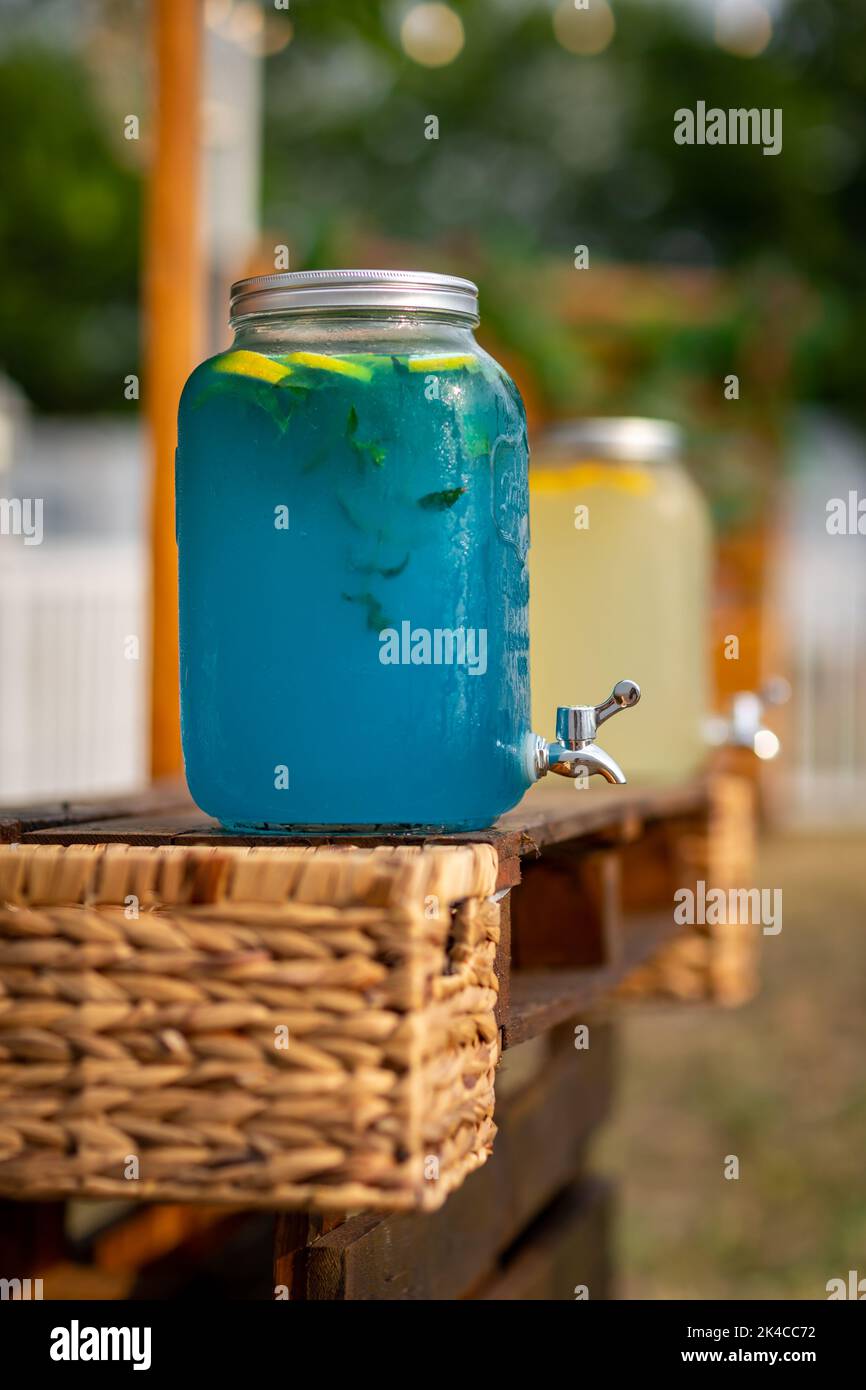 The vertical close-up view of a pouring jar filled with a blue cocktail ...