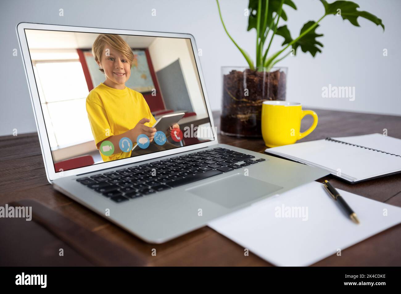 Webcam view of male student on video call on laptop on wooden table ...