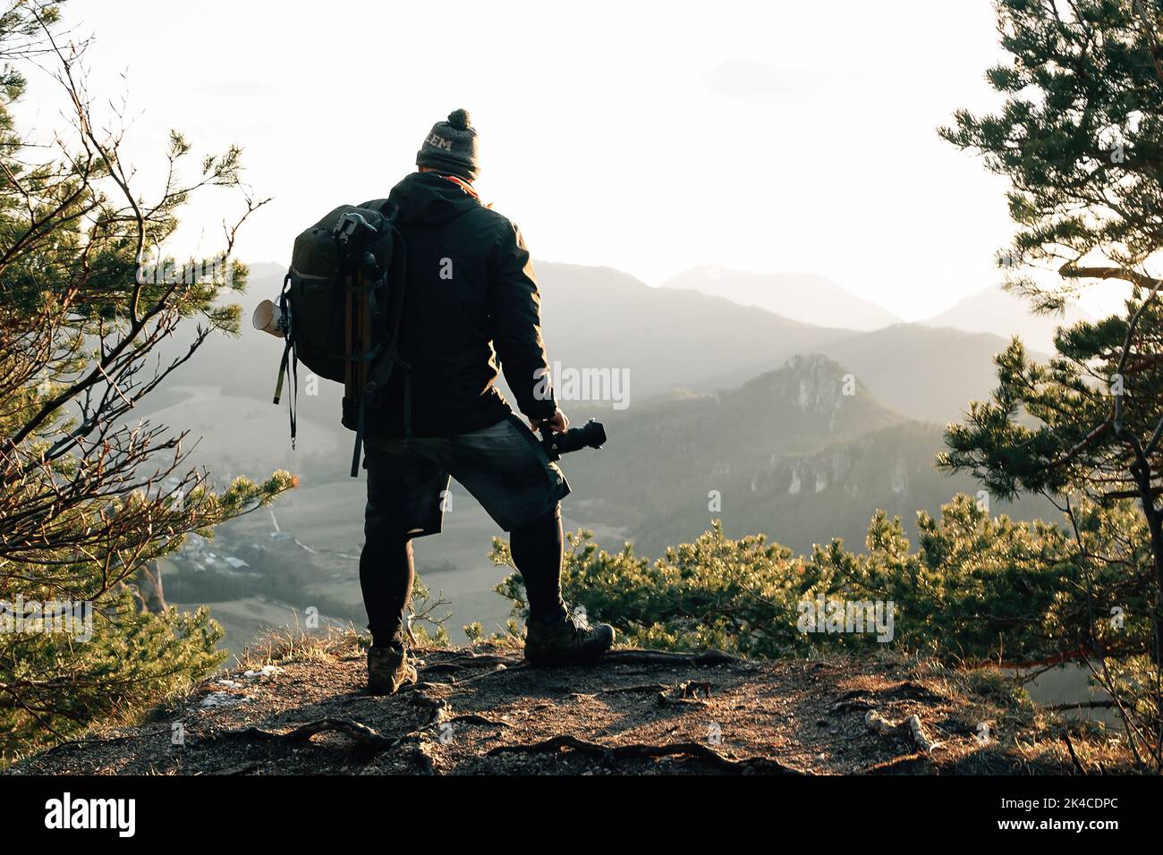 A back view of a professional hiker photographer male standing over a ...