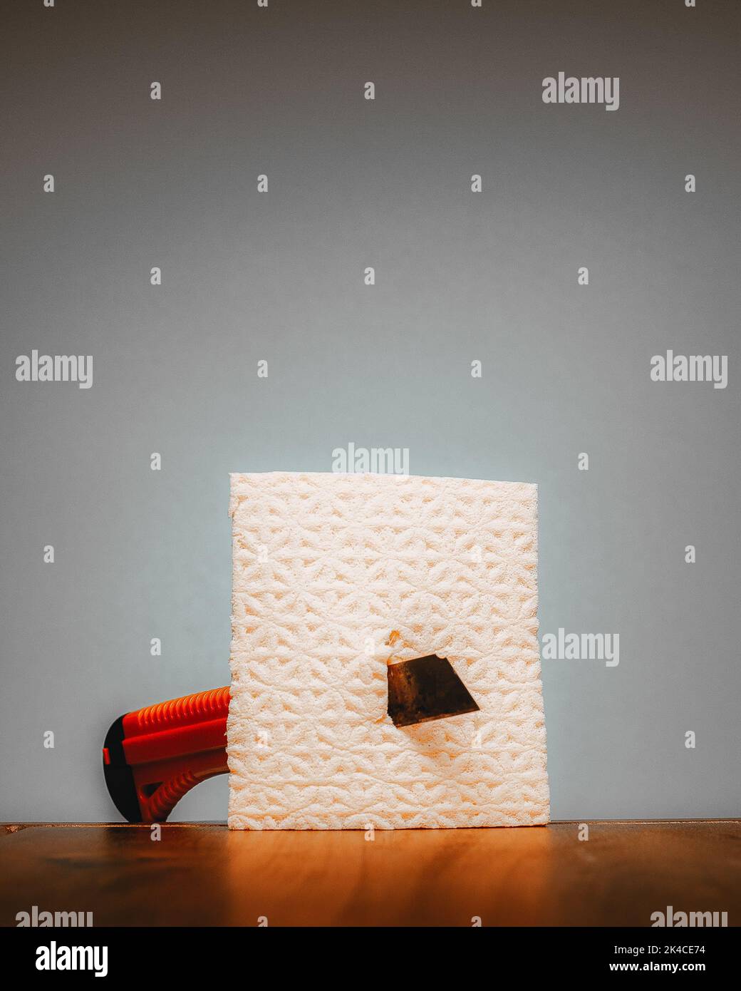 A vertical closeup of a sponge wipe pierced with a paper knife on a ...