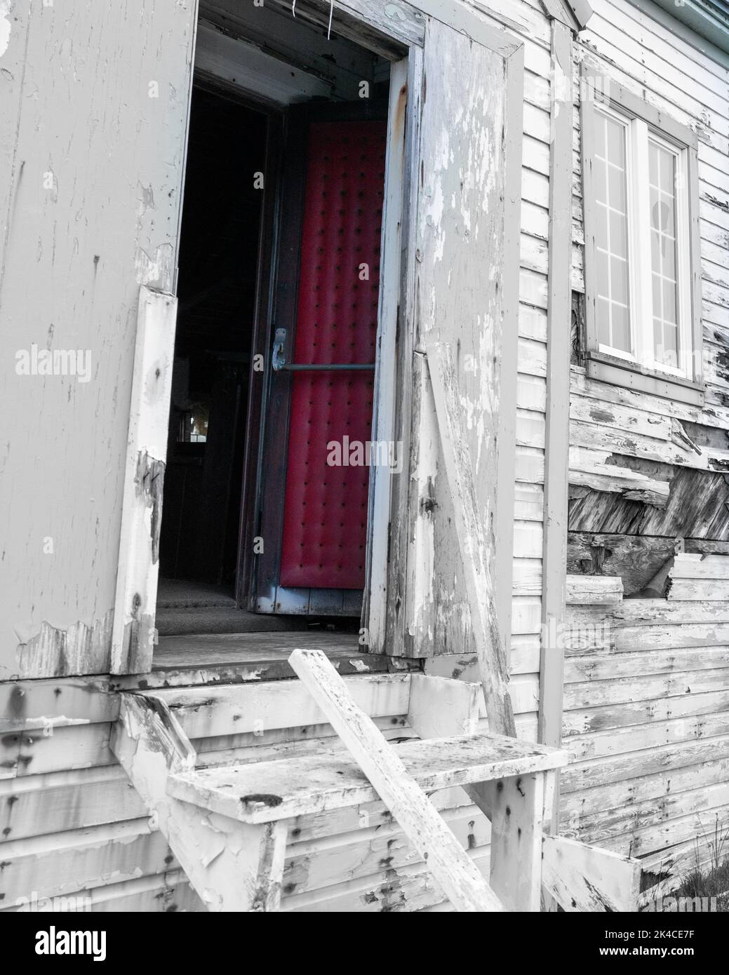 A Red door accent on the facade of the abandoned and decaying Bering ...