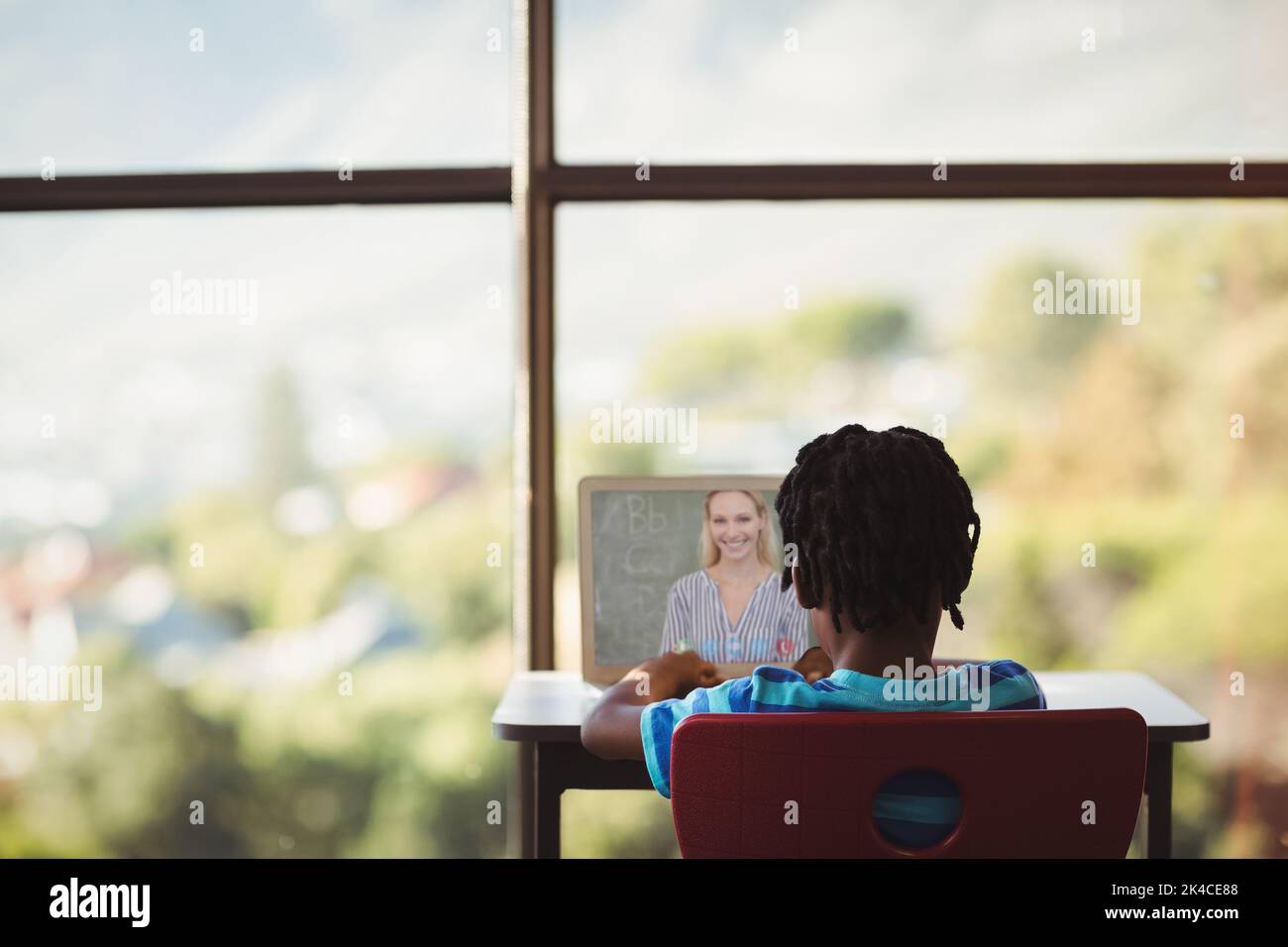 African american schoolboy using laptop on video call with female ...