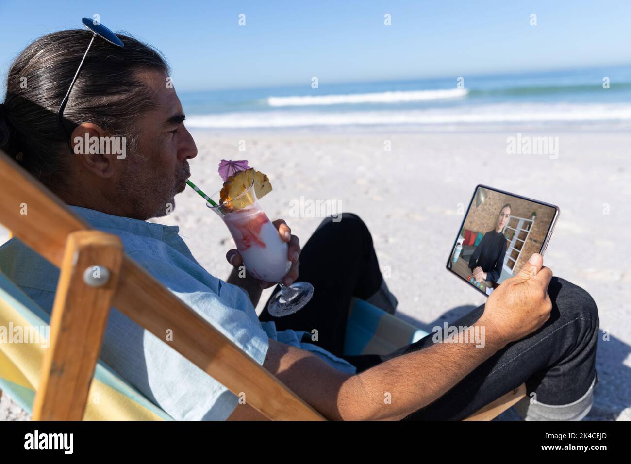 Caucasian man relaxing on beach with drink having video call using ...