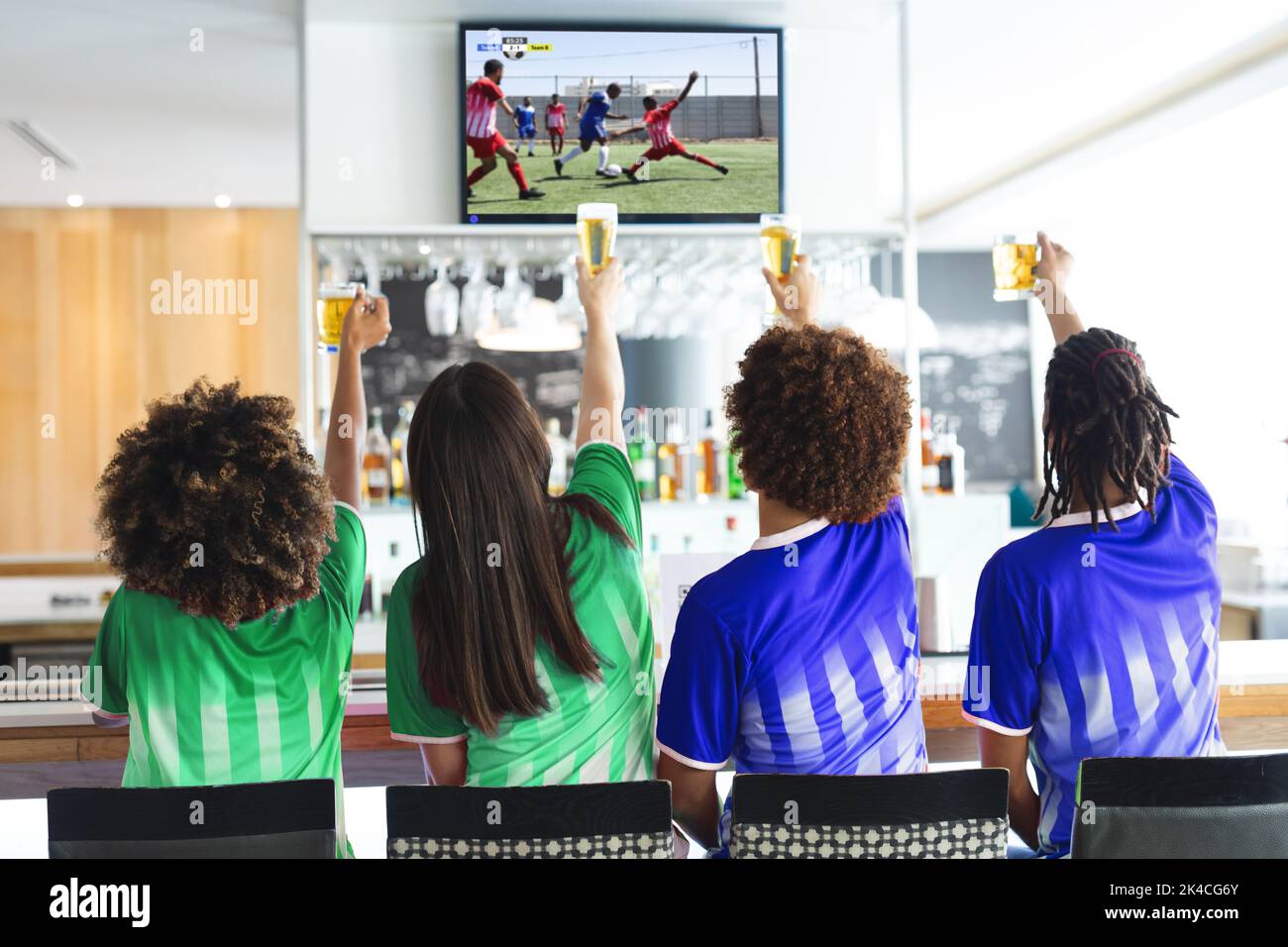 Diverse friends supporting and watching tv in bar with football match ...
