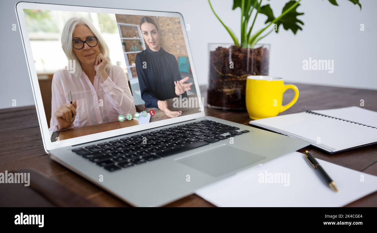 Laptop computer with a video call from businesswomen lying on desk ...