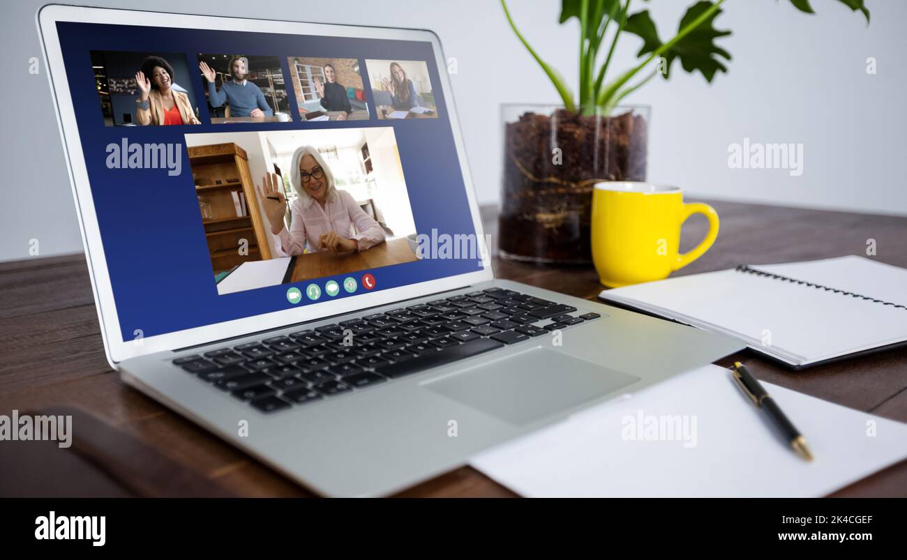 Laptop computer with a video call from businesspeople lying on desk ...