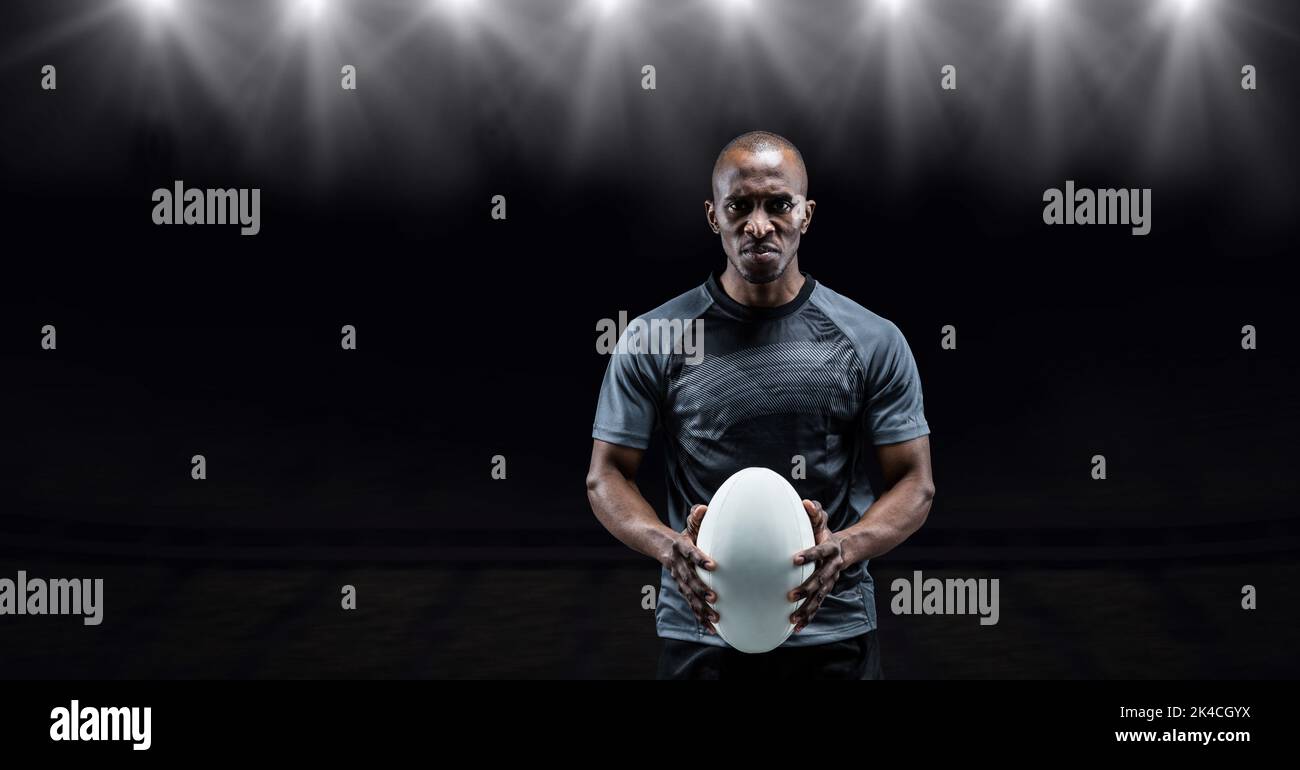 Composition of male rugby player holding rugby ball over sports stadium ...