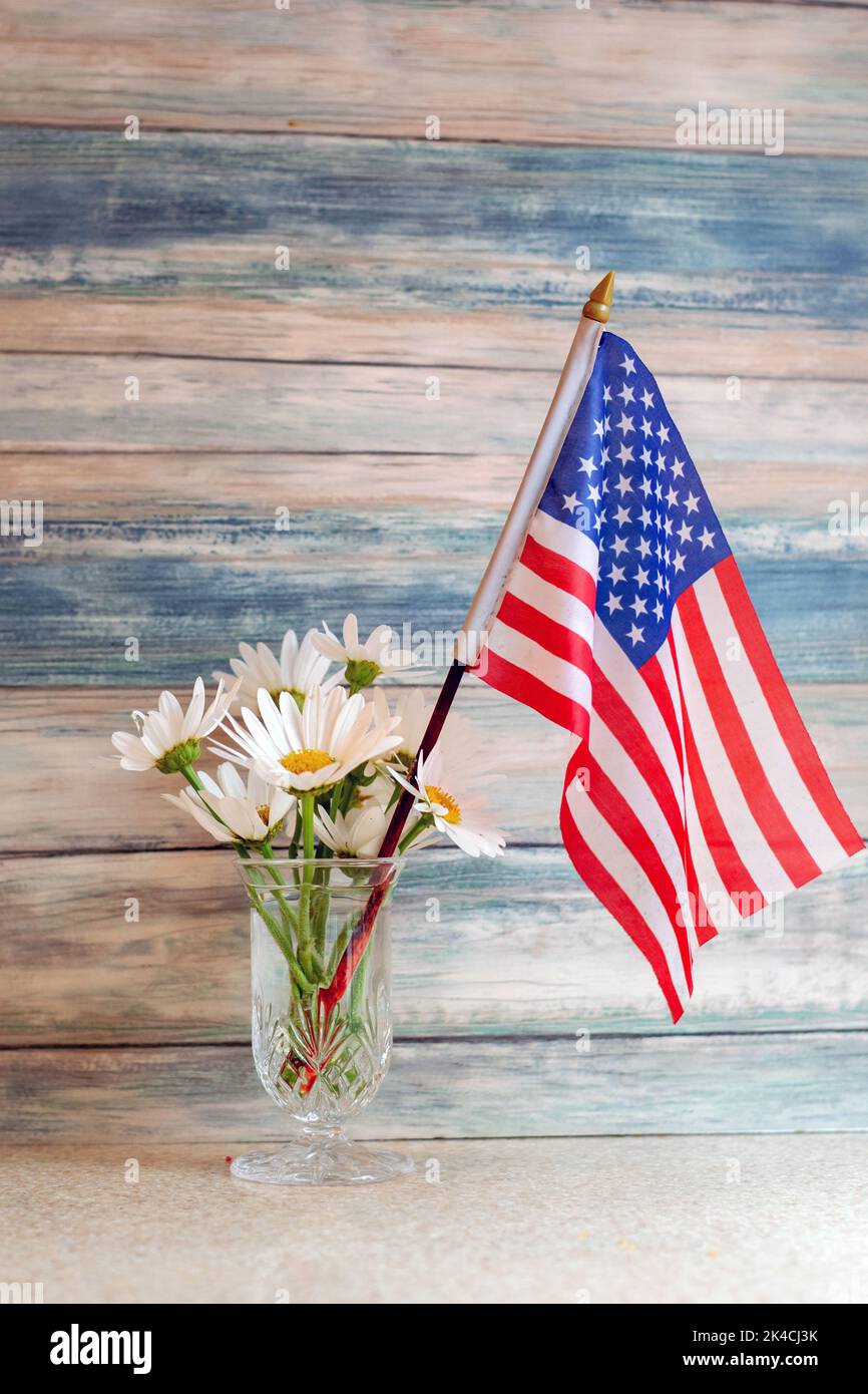 rustic still life of simple white daisies and an american flag, against ...